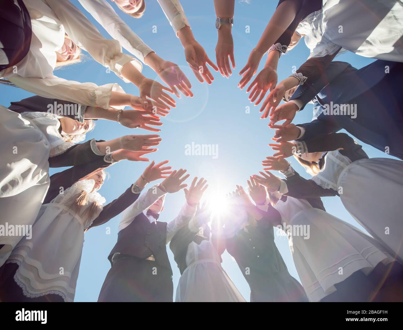 Students graduates make the shape of a circle from the palms of their ...