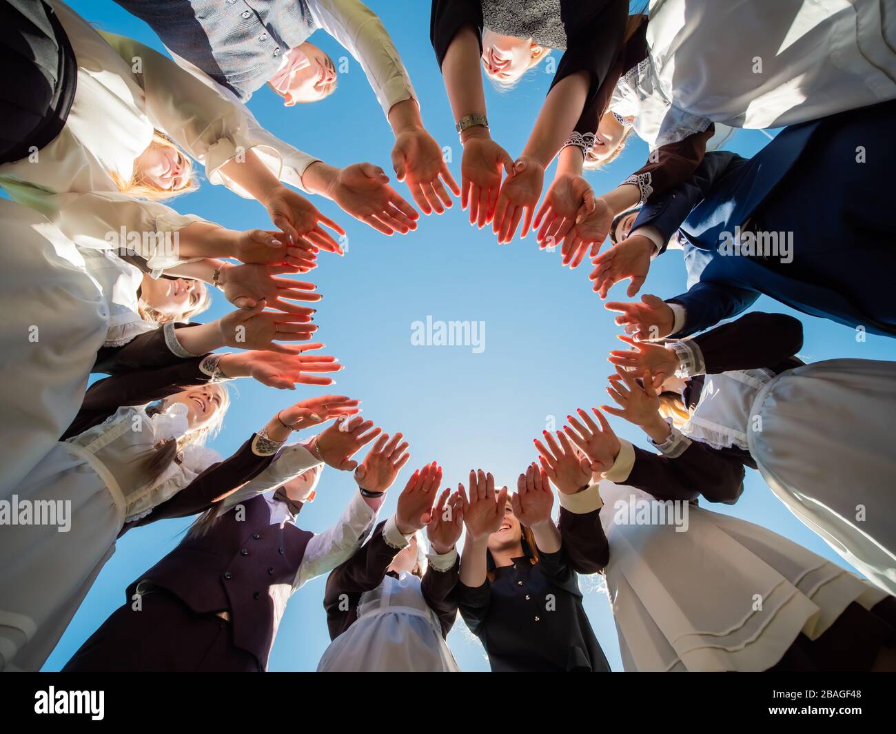 Students graduates make the shape of a circle from the palms of their ...