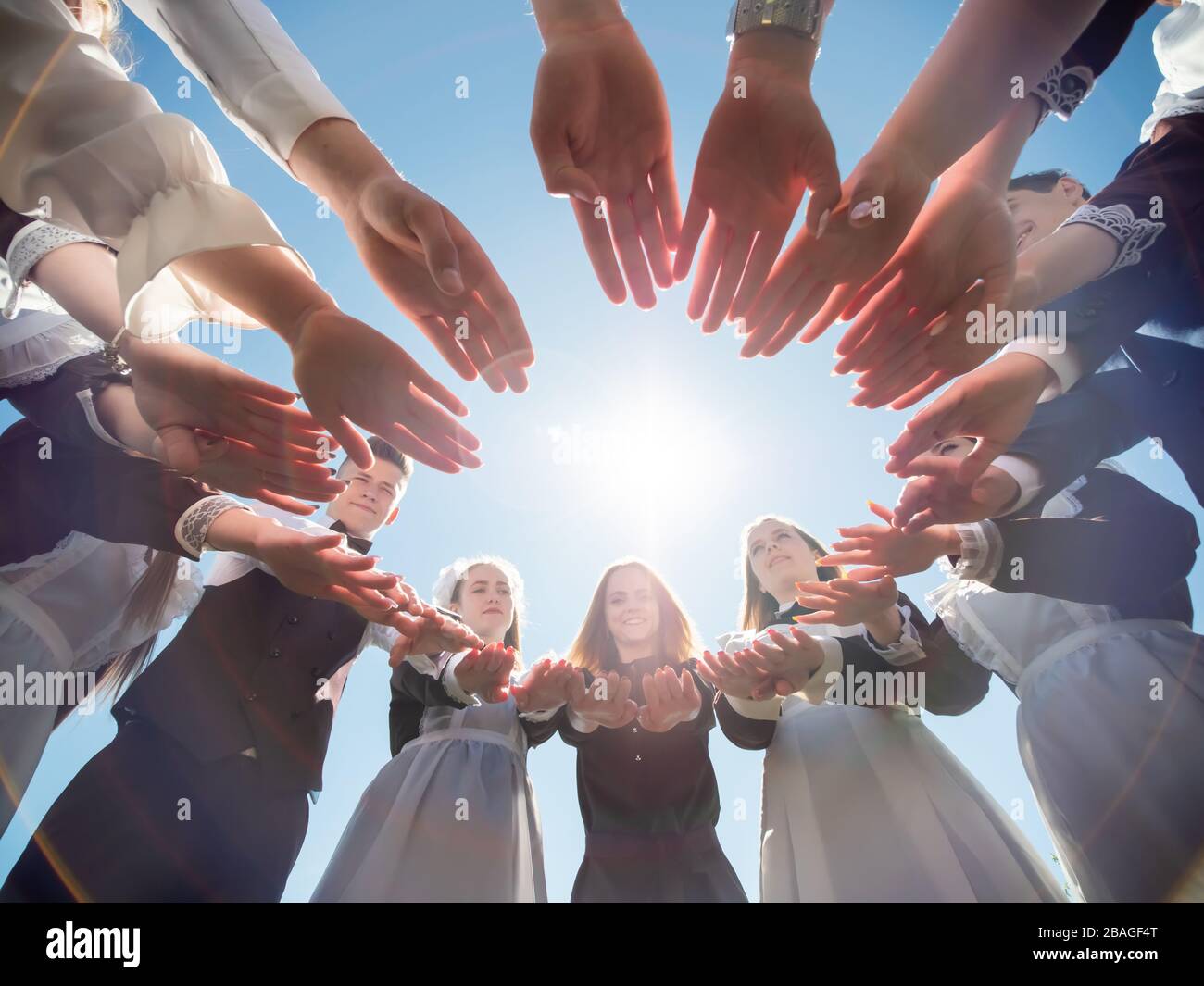Students graduates make the shape of a circle from the palms of their ...