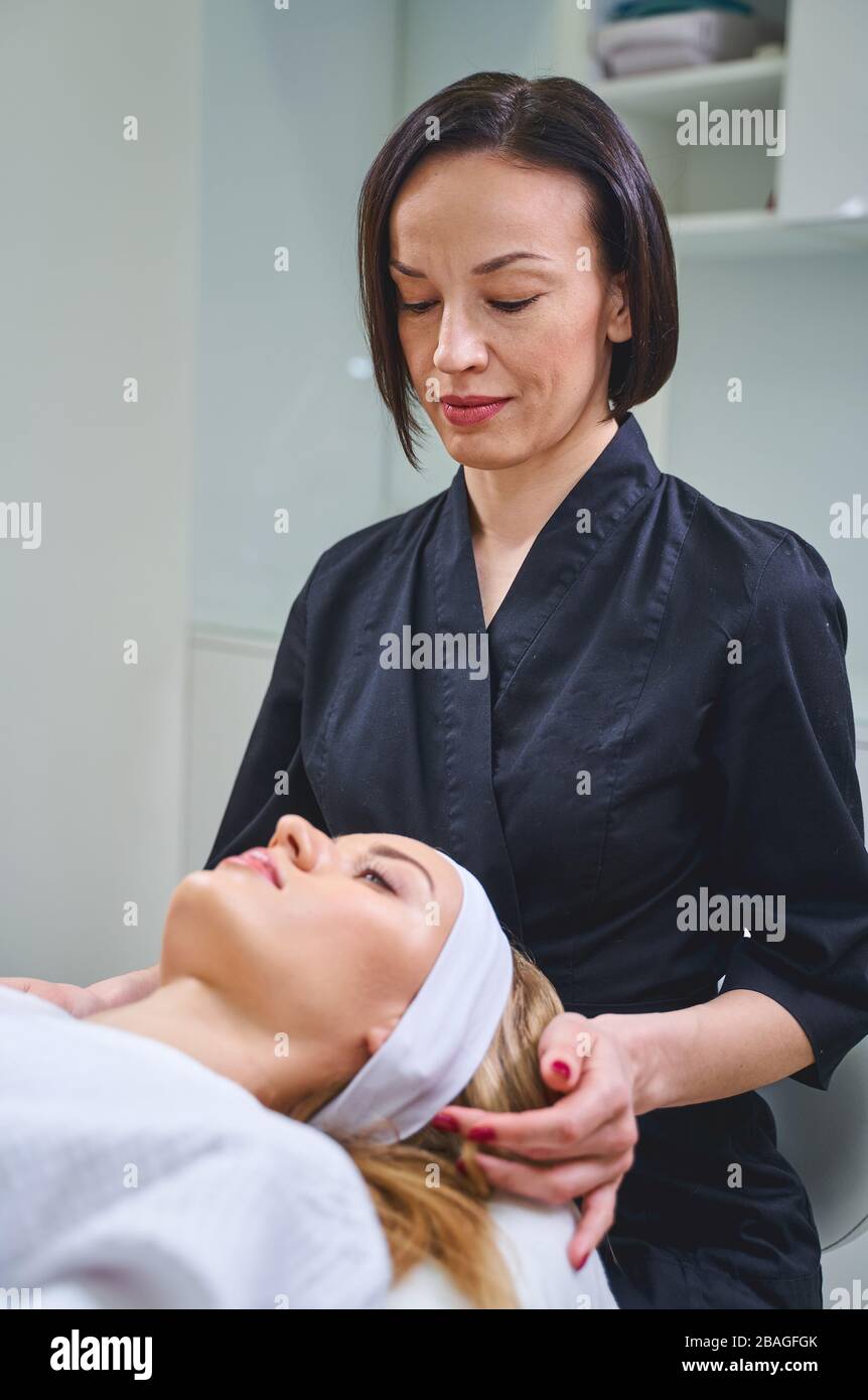 Professional beautician working her client in salon Stock Photo - Alamy