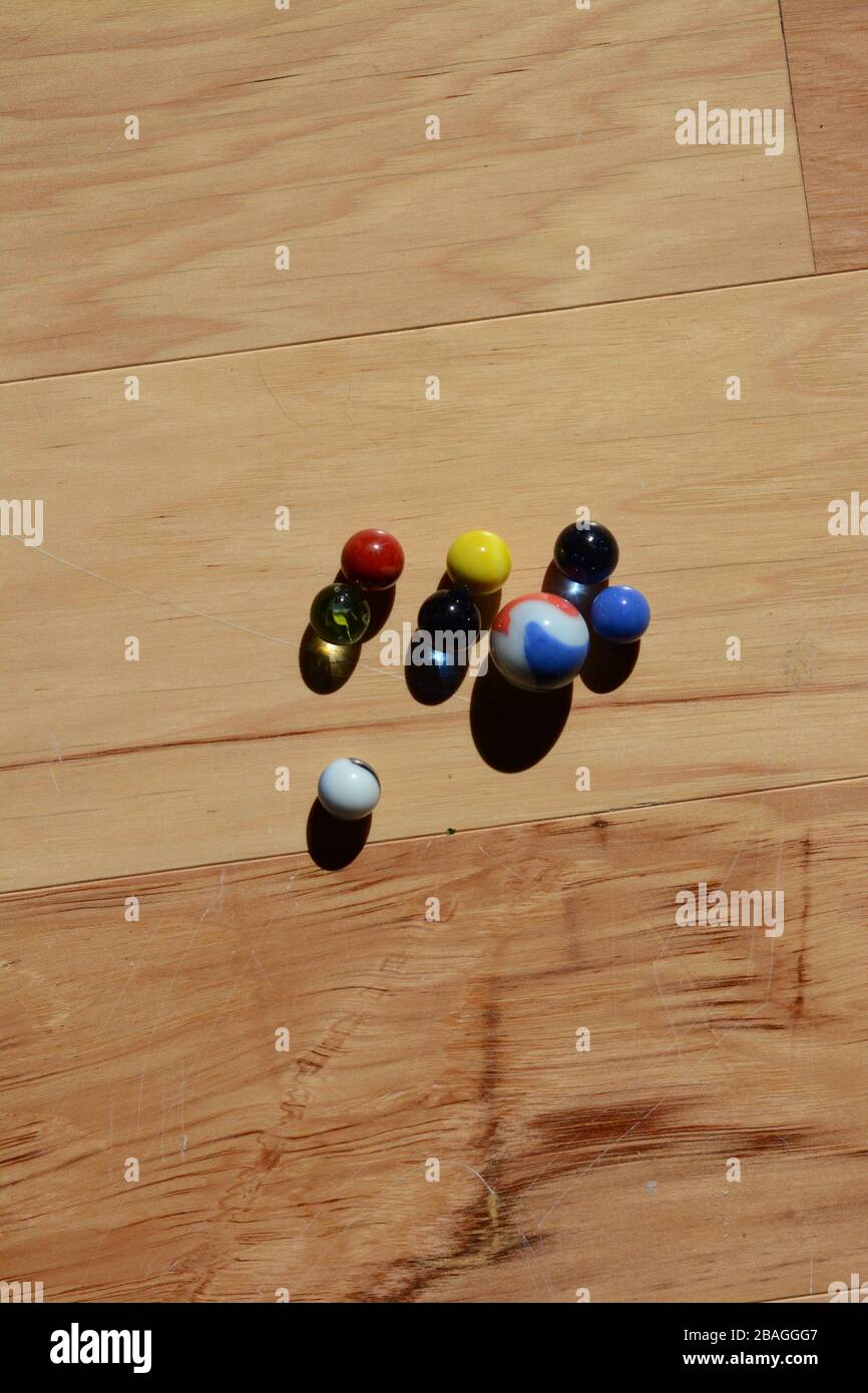 Old-fashioned glass marbles on a wooden floor. Sunshine and shadow ...