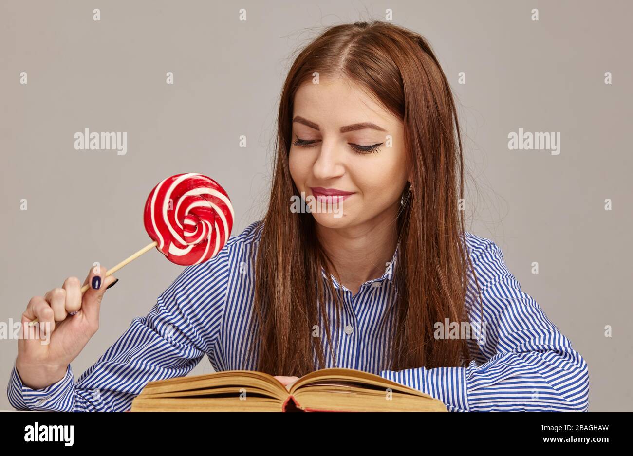 woman reading books at home, she also enjoys delicious candy Stock ...