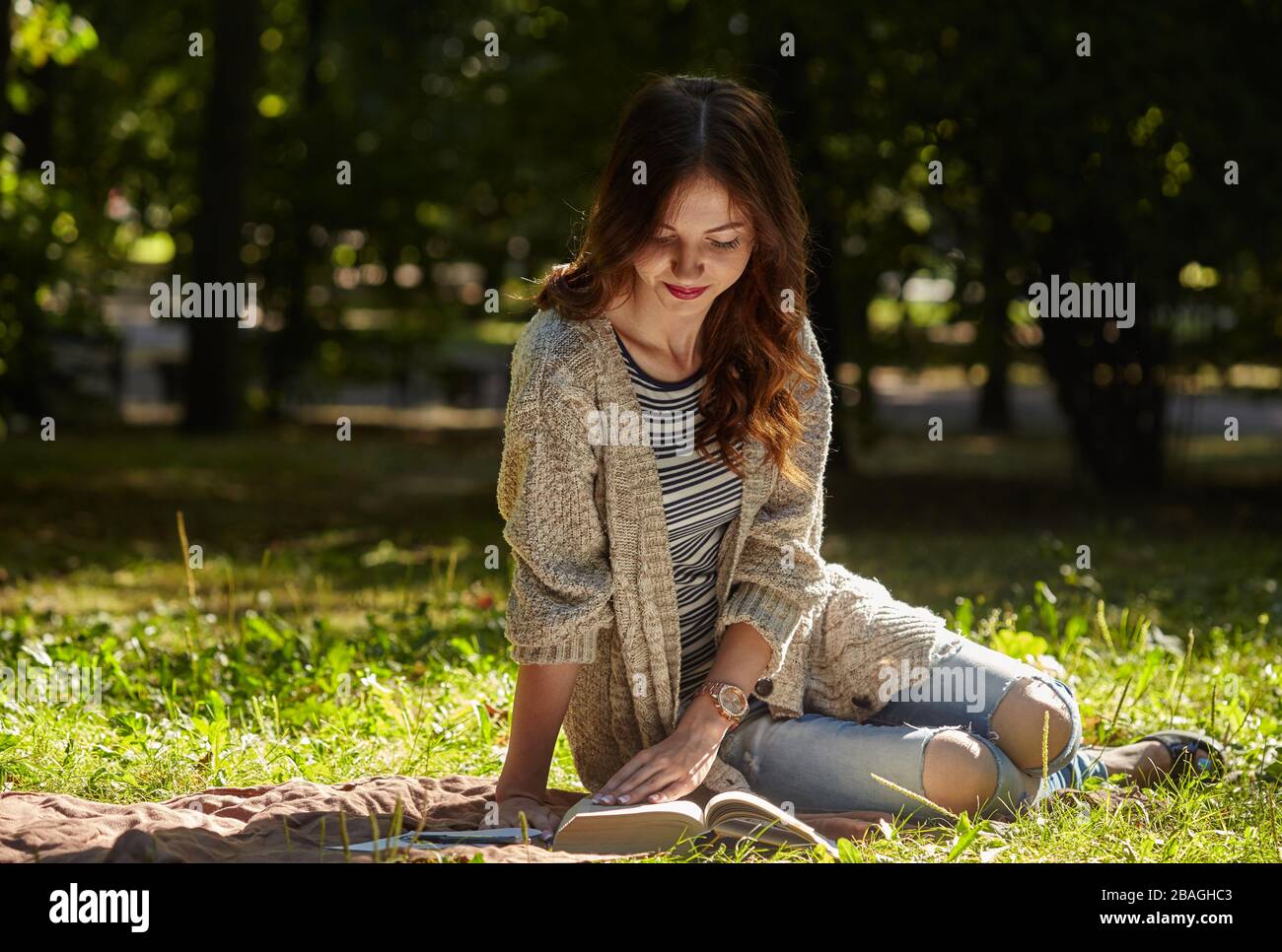 young woman sitting in the quiet green grass and reading a book Stock ...