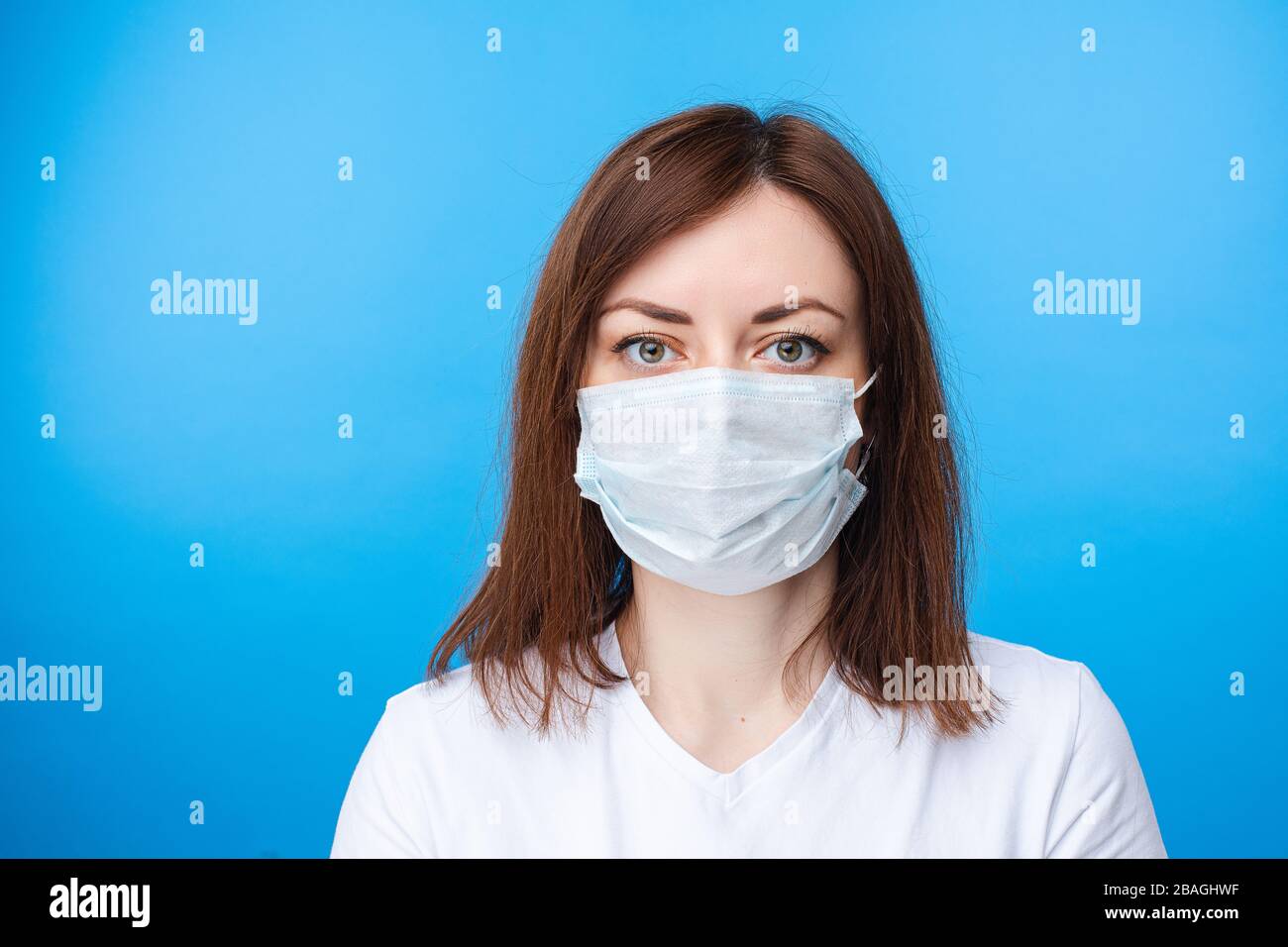 Brunette woman wearing aseptic mask. light blue background Stock Photo ...