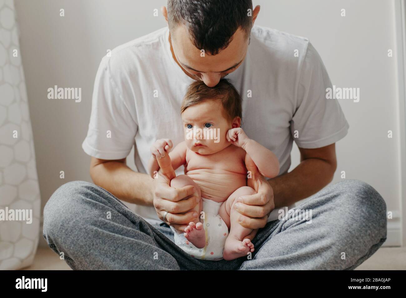 Happy Caucasian father holding newborn baby on laps knees. Man parent ...