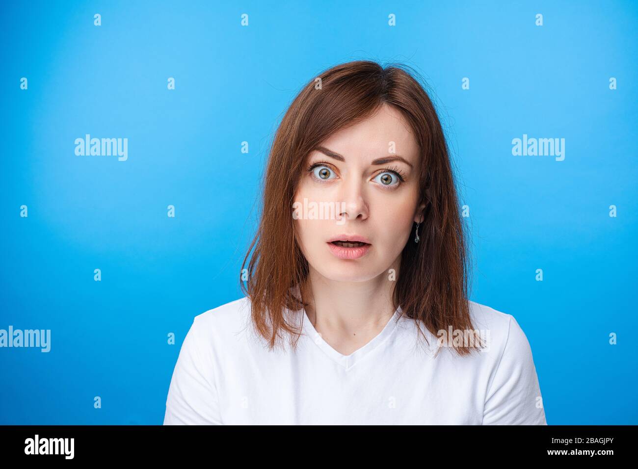 Scared brunette woman looking at camera. light blue background Stock ...
