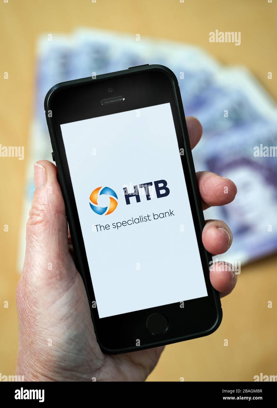 A woman looking at the Hampshire Trust Bank logo on a mobile phone ...