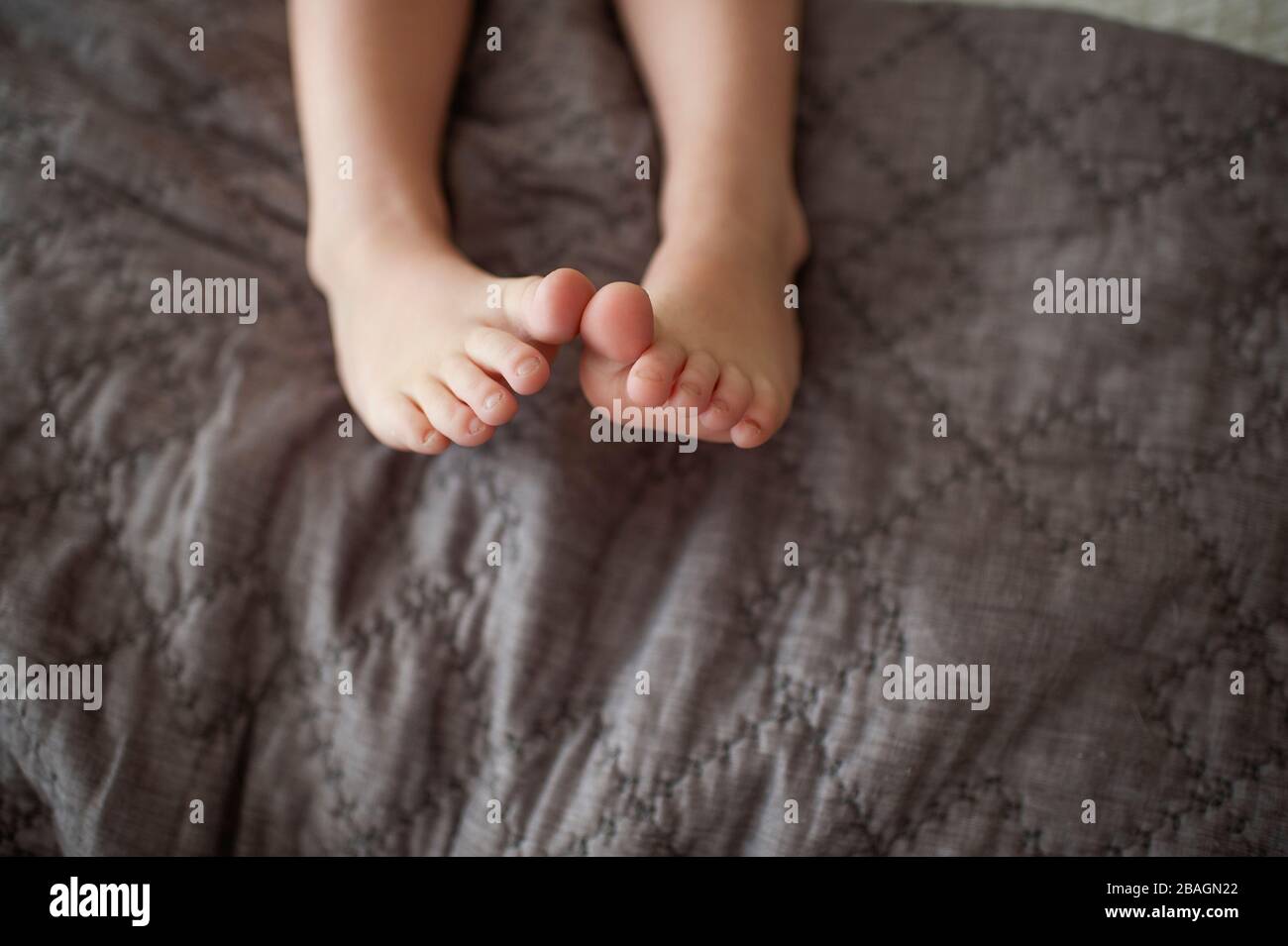 Toddler feet with toes touching on bed at home Stock Photo - Alamy