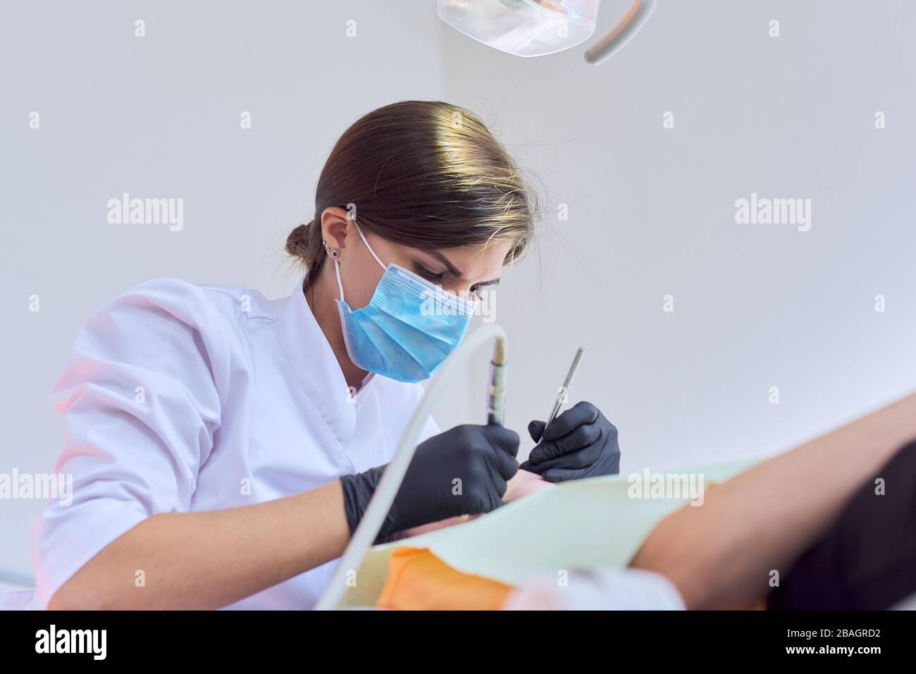 Woman doctor dentist treating teeth to girl patient in dental office ...