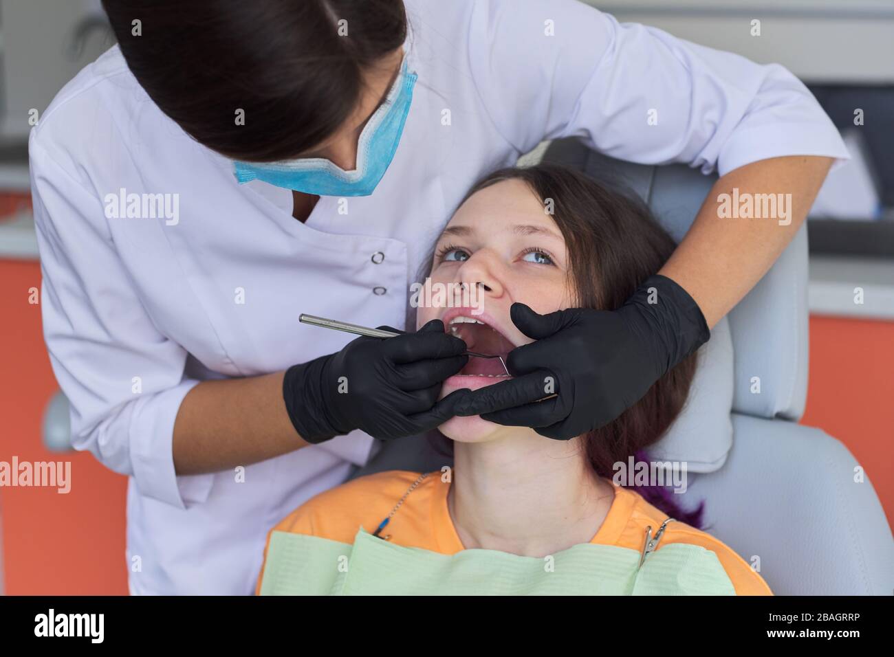 Woman doctor dentist treating teeth to girl patient in dental office ...