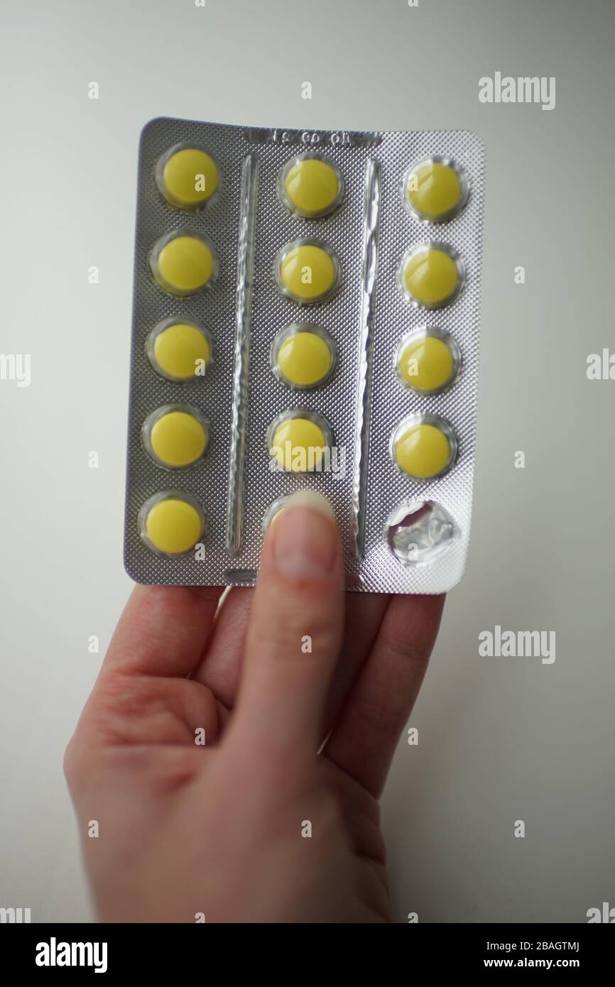Blister with yellow vitamins or pills in a female fingers, top view ...