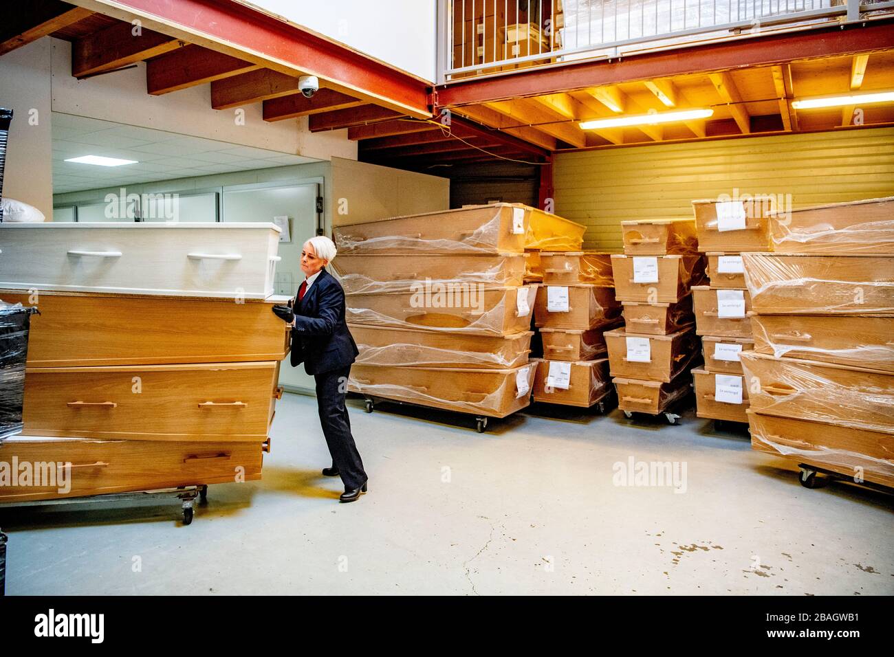 An employee of a funeral company arranges coffins in a storage.Funeral ...