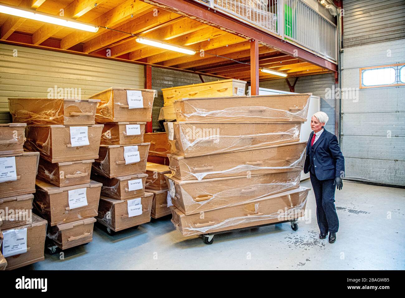 An employee of a funeral company arranges coffins in a storage.Funeral ...