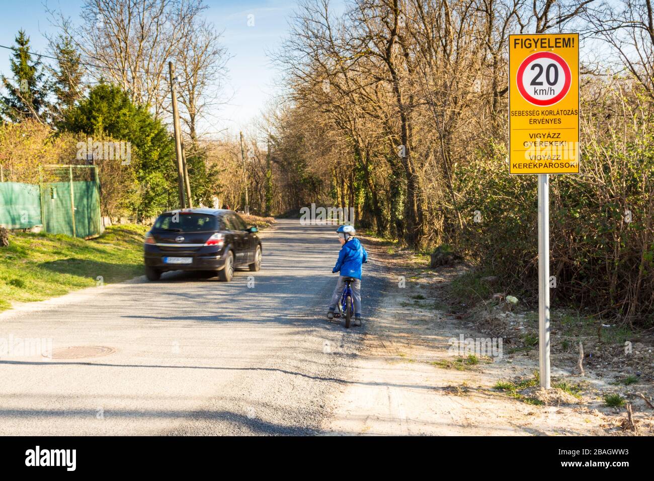 Child kid on bike waiting for car passing on road with 20 km/h speed ...