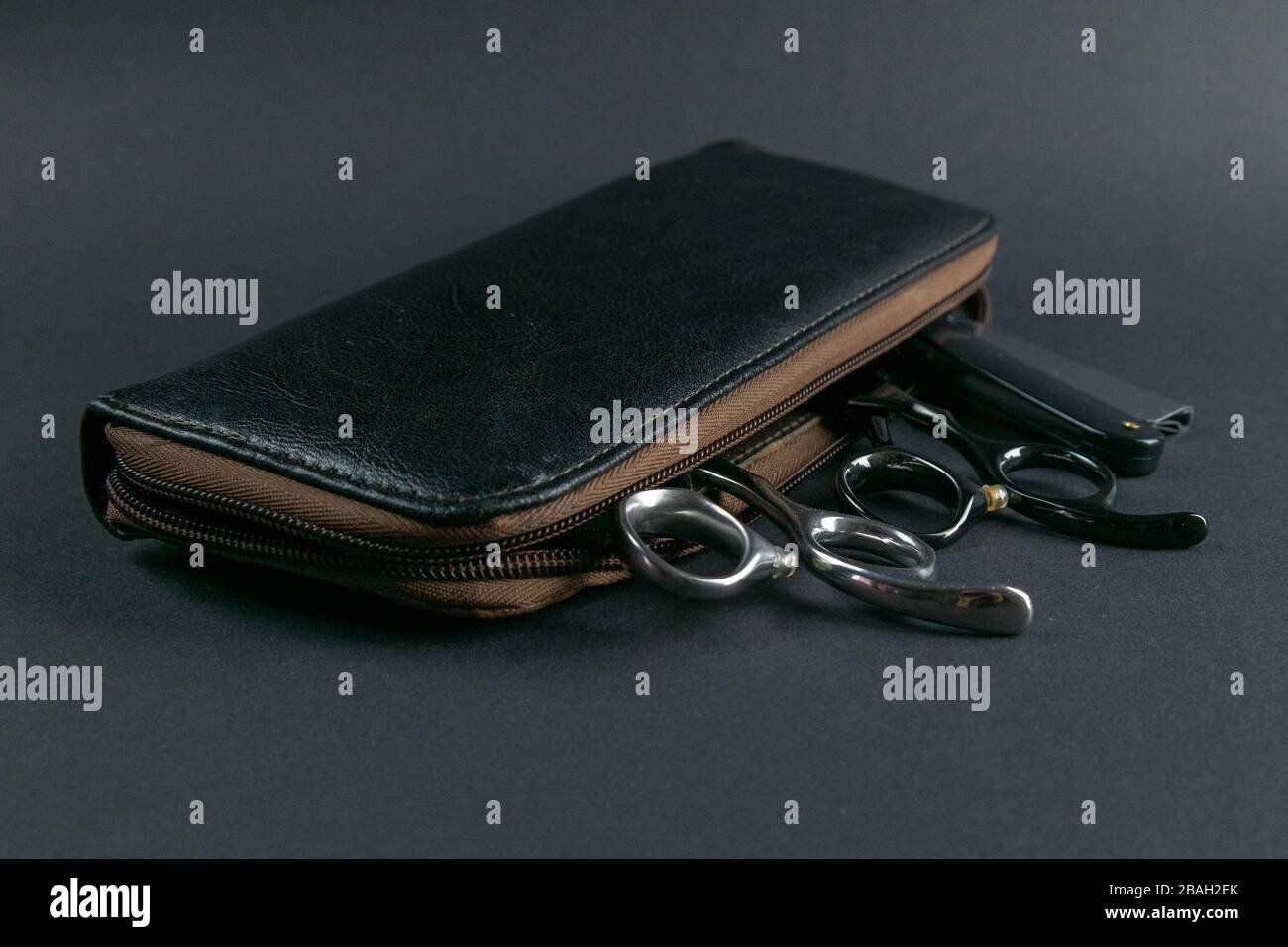 Scissors, combs, a dangerous razor in a special case on black ...