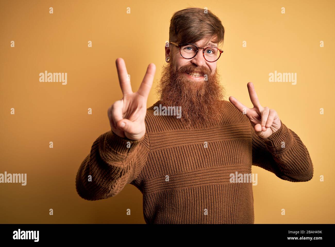 Handsome Irish redhead man with beard wearing glasses and winter ...