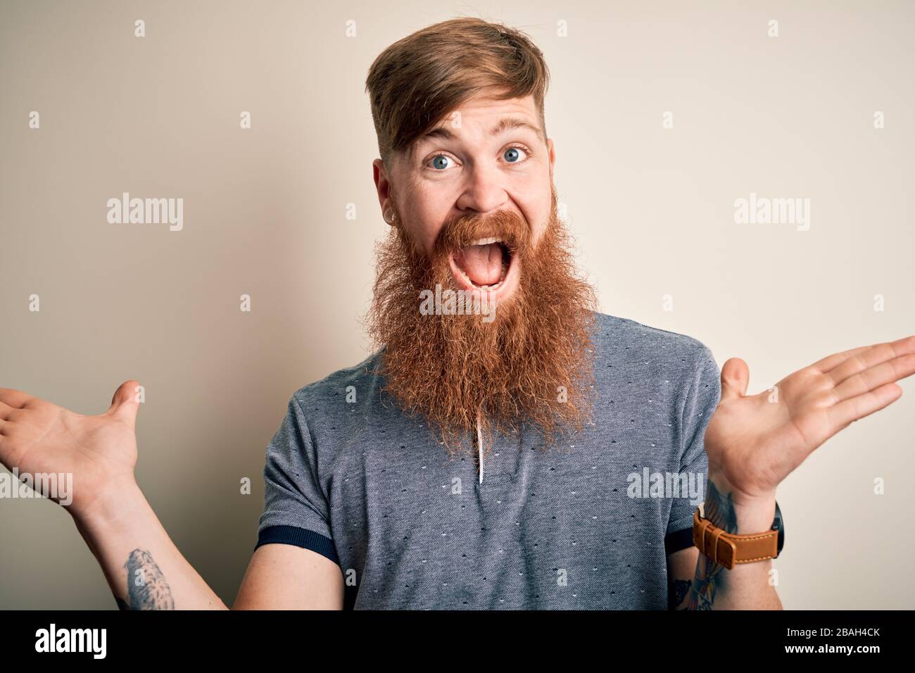 Handsome Irish redhead man with beard and arm tattoo standing over ...