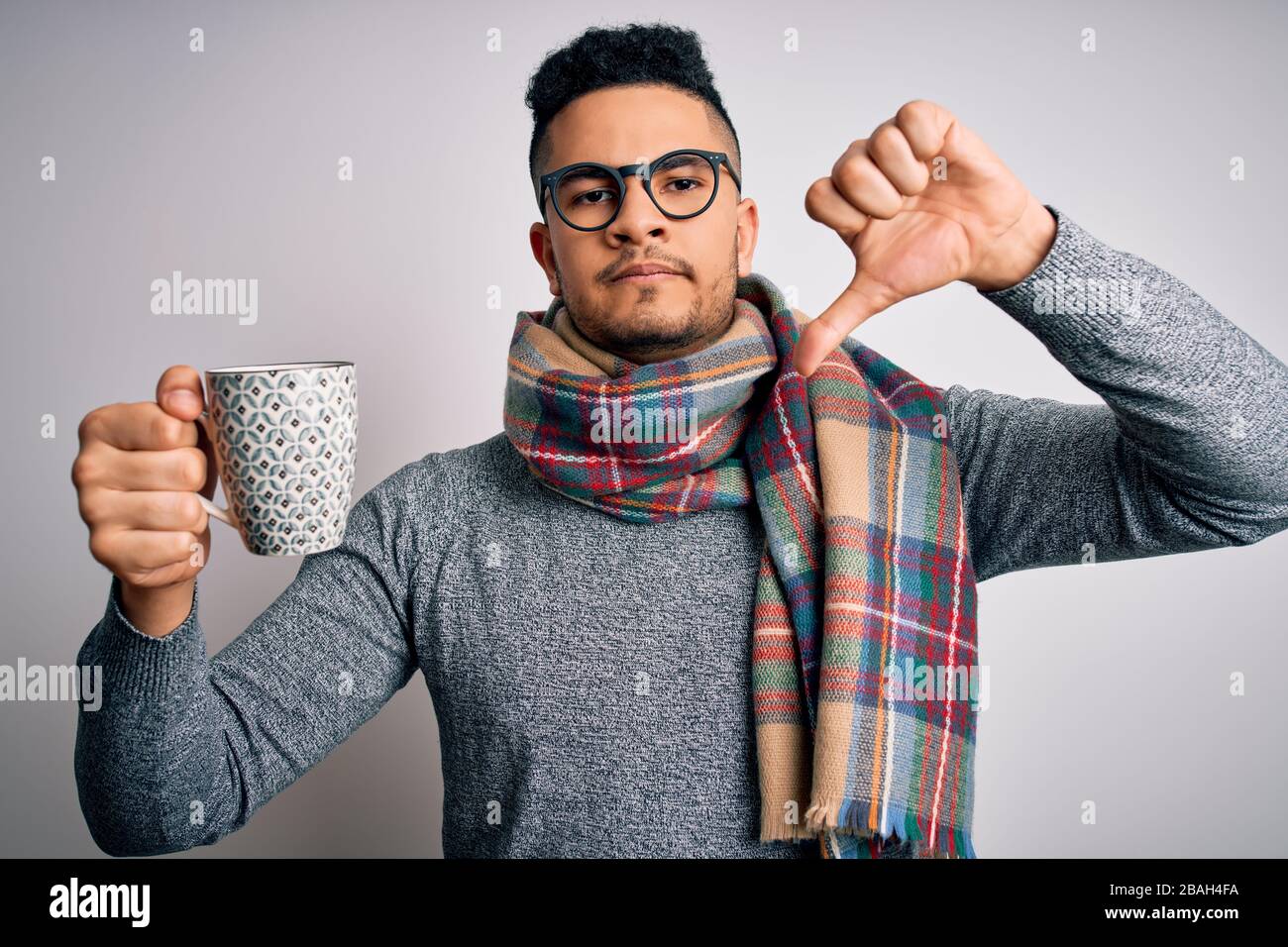 Young handsome man wearing scarf drinking mug of hot coffe over ...