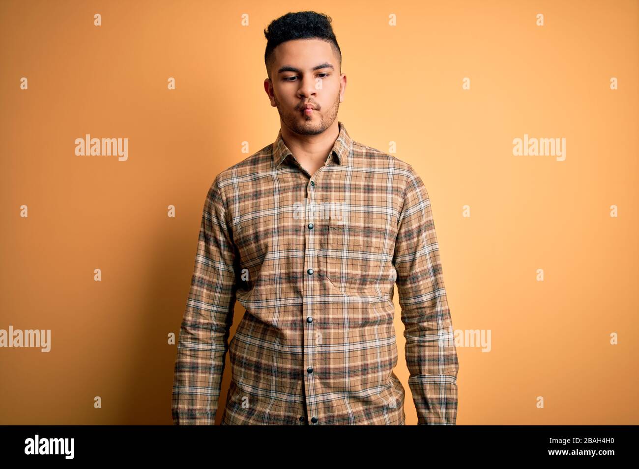 Young handsome man wearing casual shirt standing over isolated yellow ...