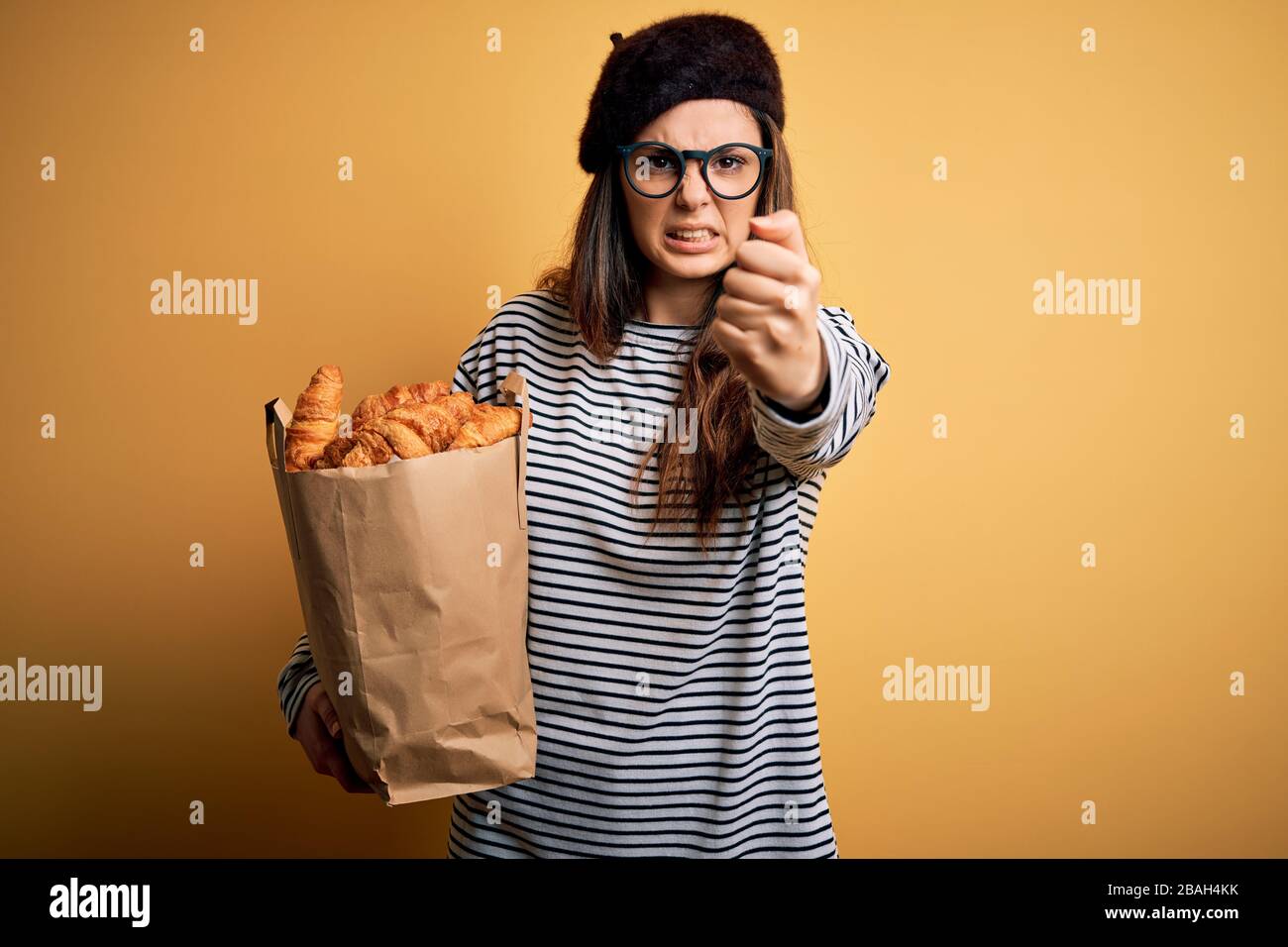 Young beautiful brunette french woman wearing beret holding bag with ...