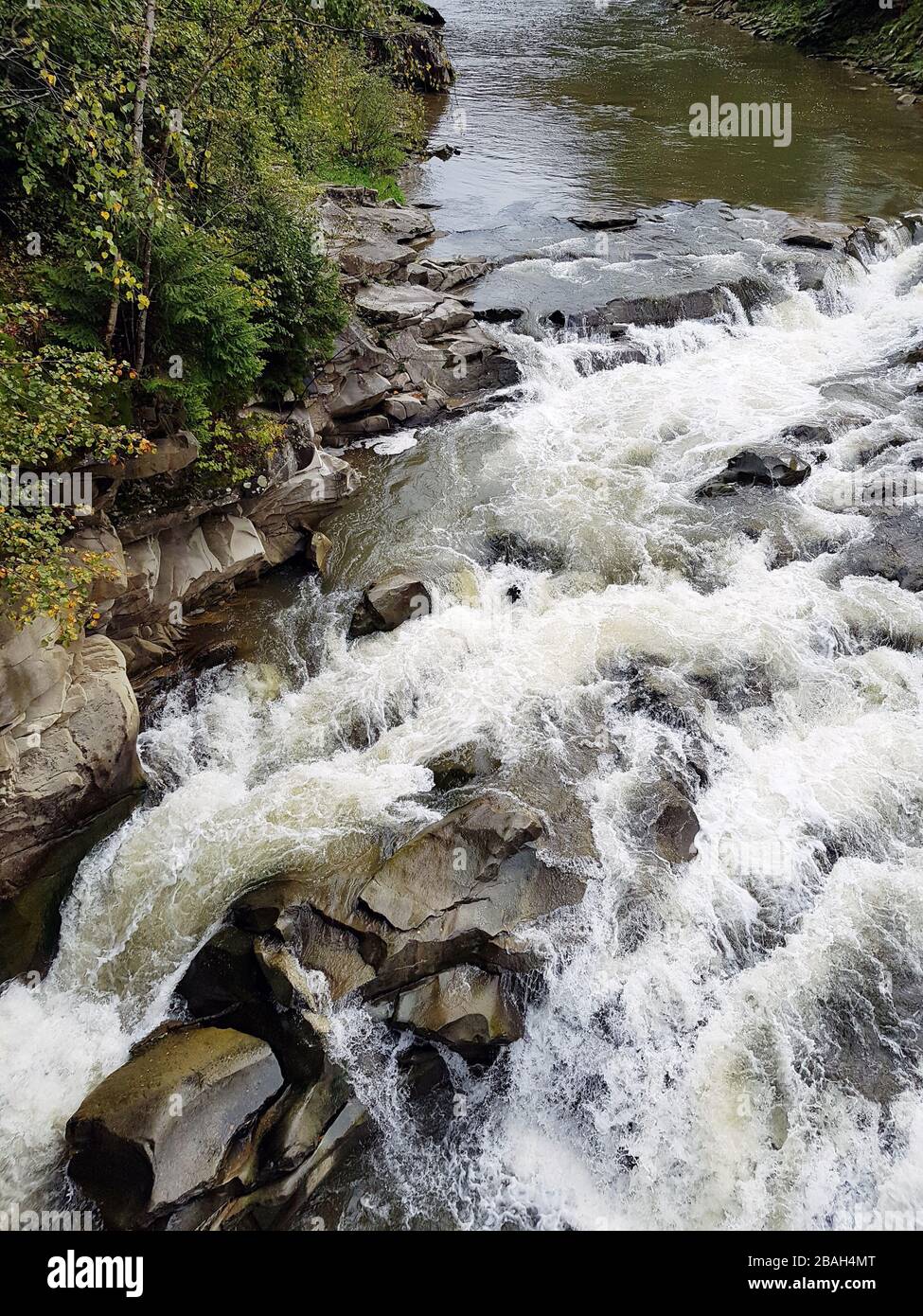 Strong streams of water in the river in the fall. River stone rapids in ...