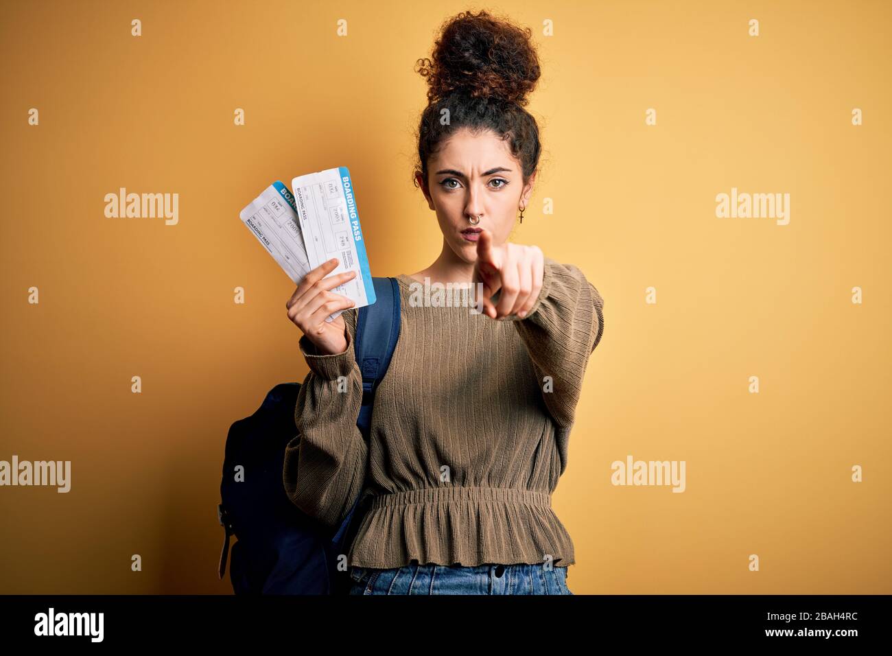 Beautiful tourist woman with curly hair and piercing wearing backpack ...