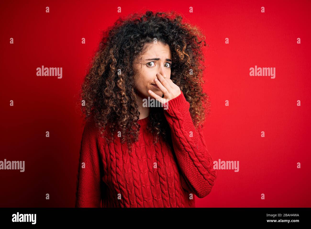 Young beautiful woman with curly hair and piercing wearing casual red ...