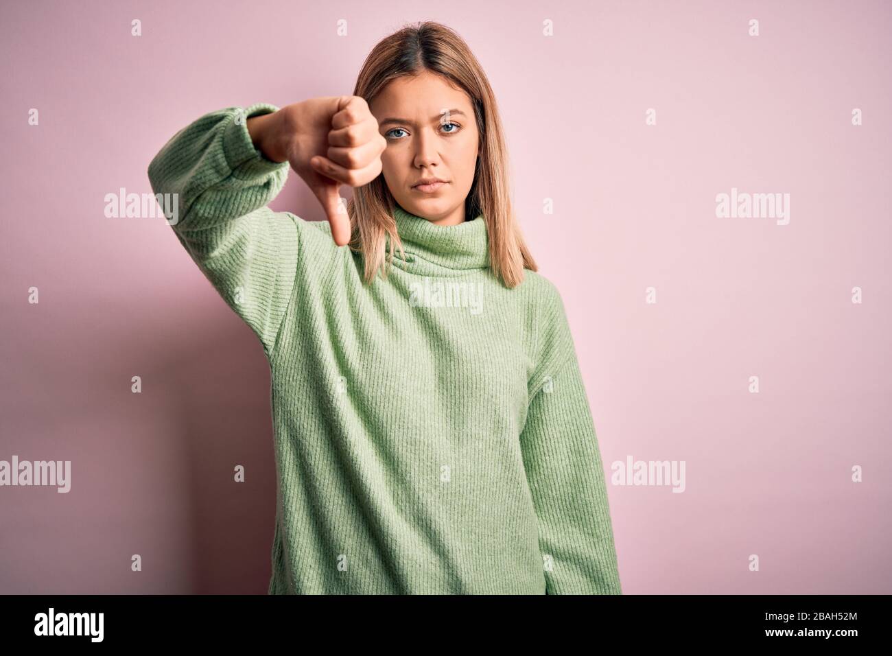 Young beautiful blonde woman wearing winter wool sweater over pink ...