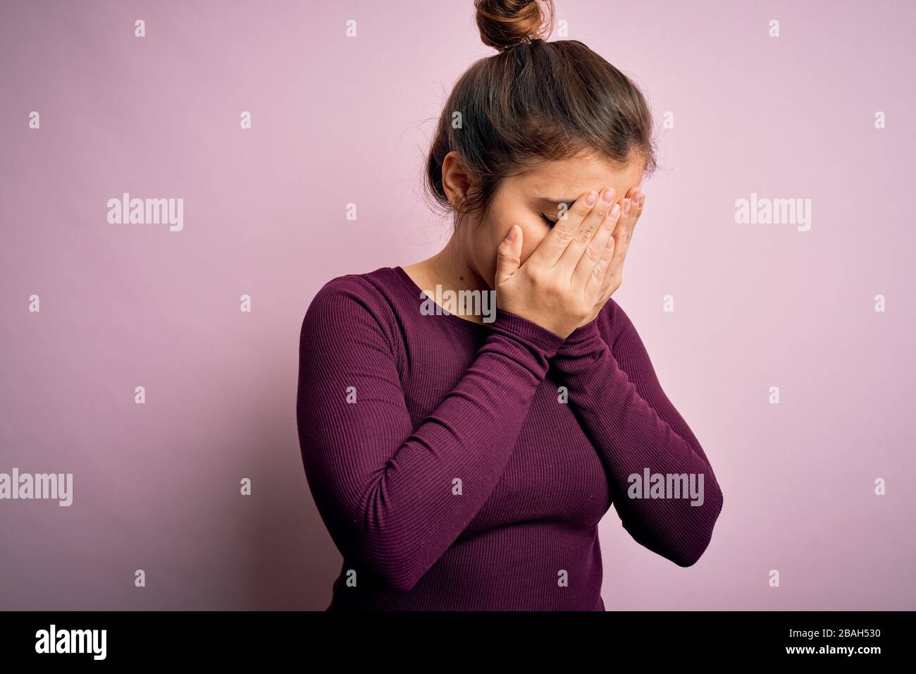 Beautiful young woman wearing casual bun hairstyle over pink isolated ...