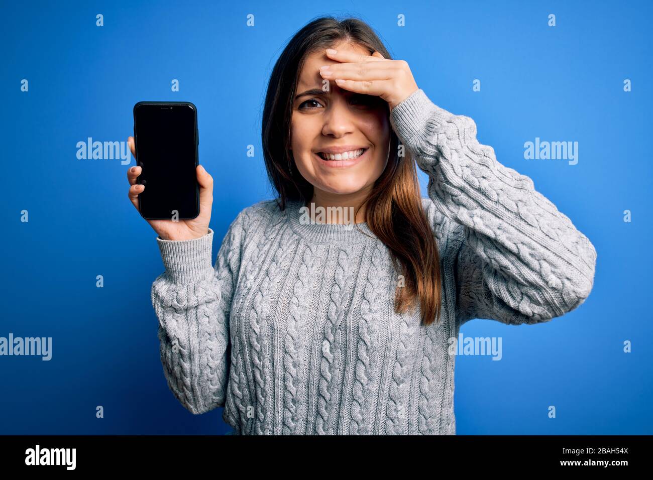 Young woman showing blank smartphone screen over blue isolated ...