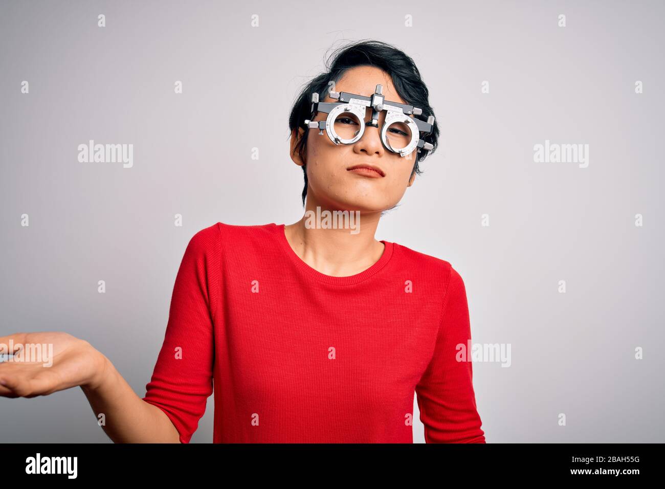 Young beautiful asian girl wearing optometry glasses standing over ...