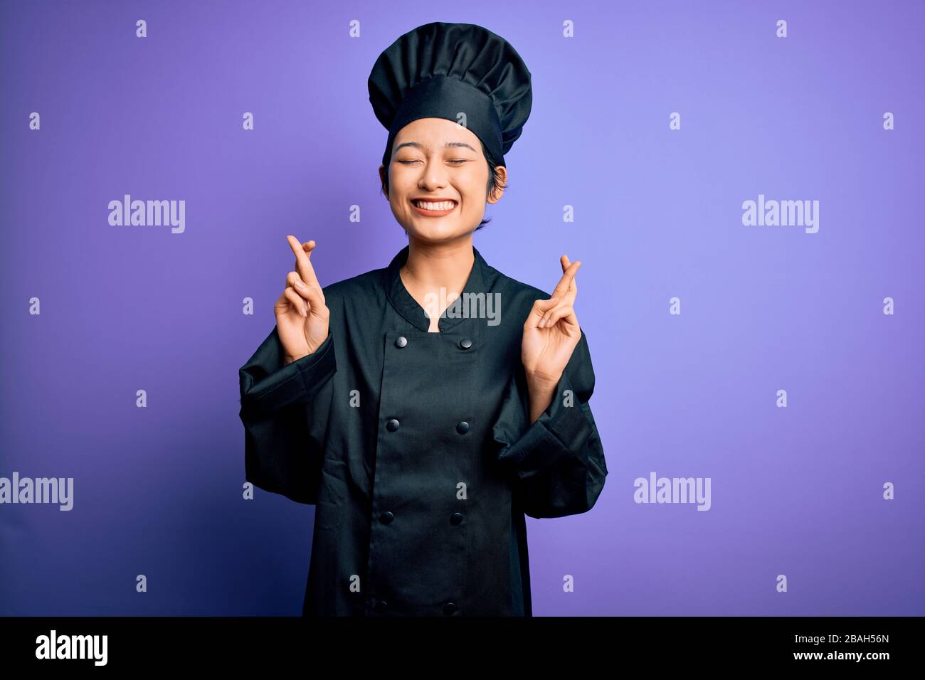 Young beautiful chinese chef woman wearing cooker uniform and hat over ...