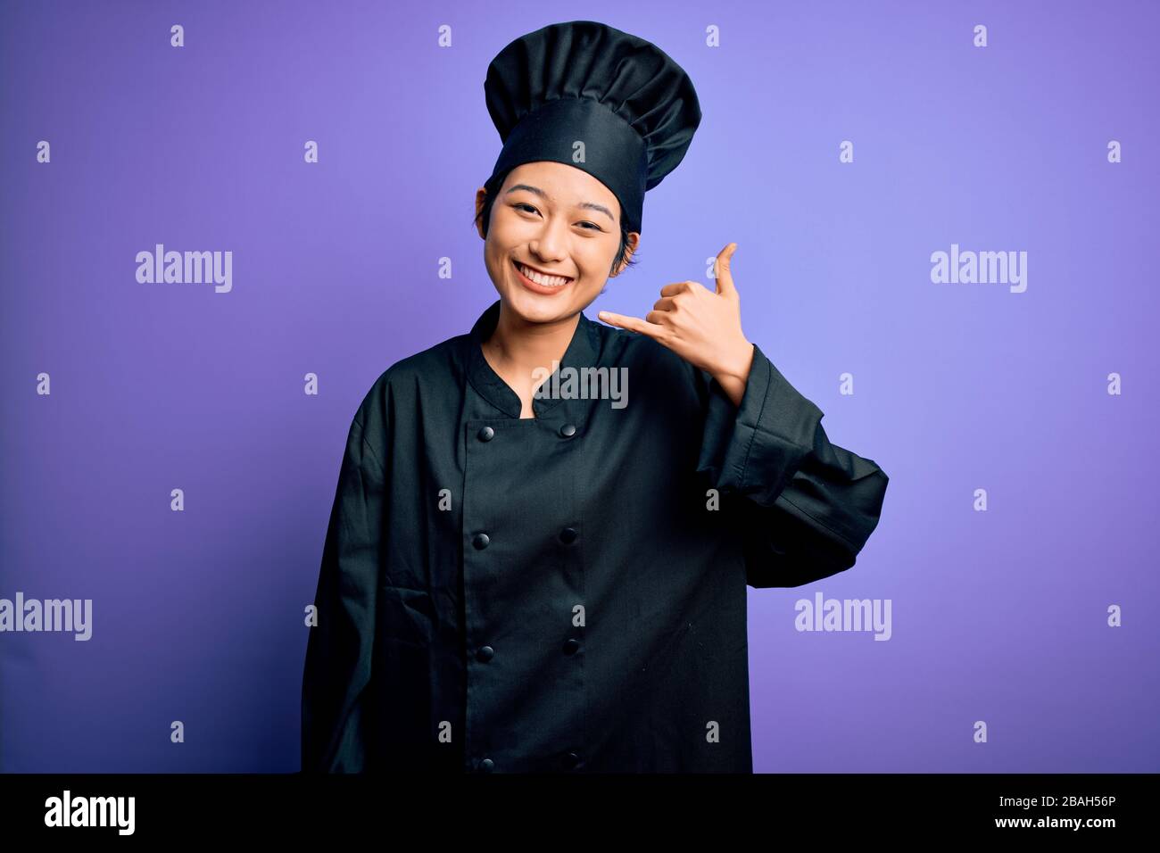 Young beautiful chinese chef woman wearing cooker uniform and hat over ...