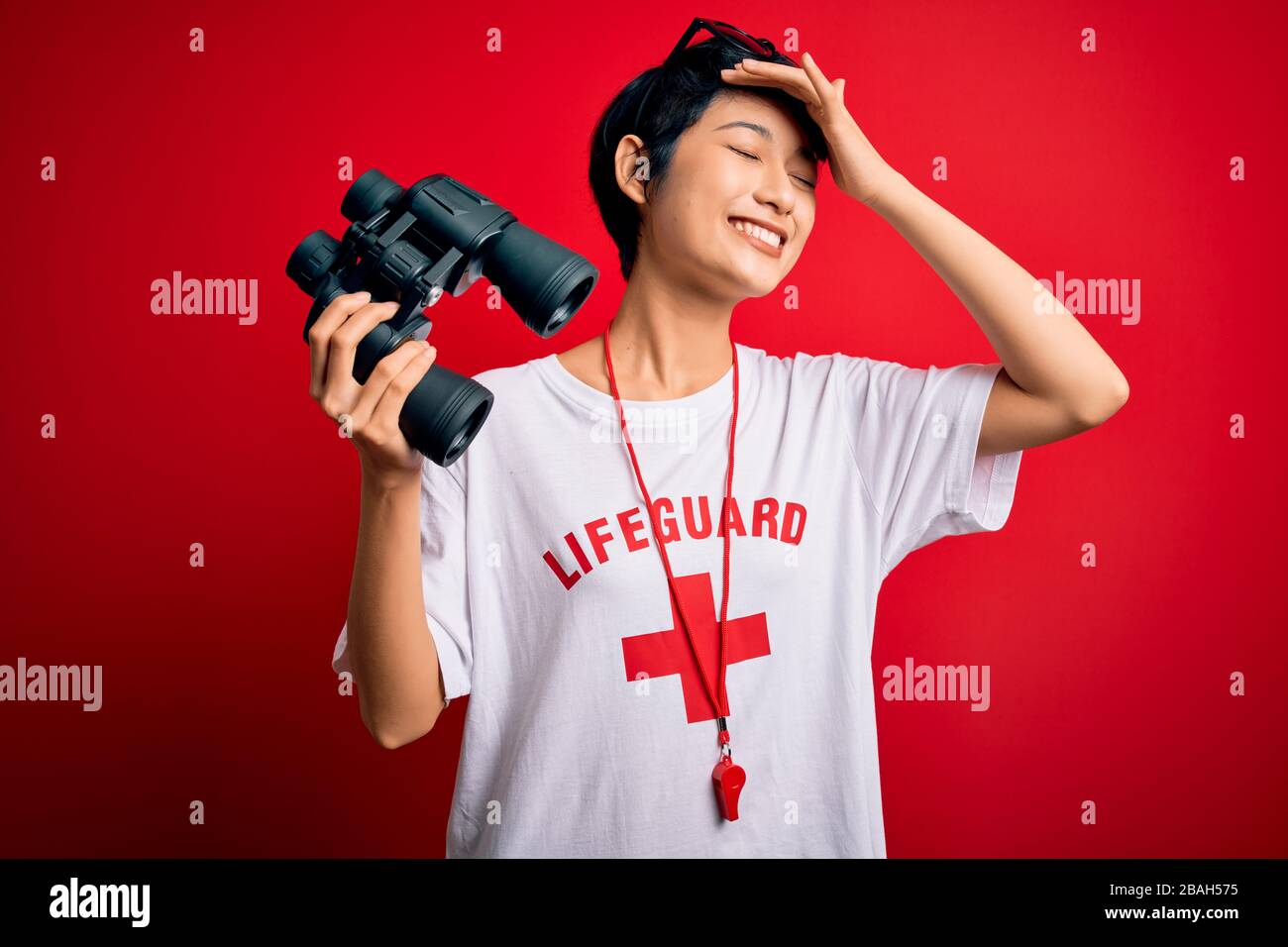 Young beautiful asian lifeguard girl using whistle and binoculars over ...