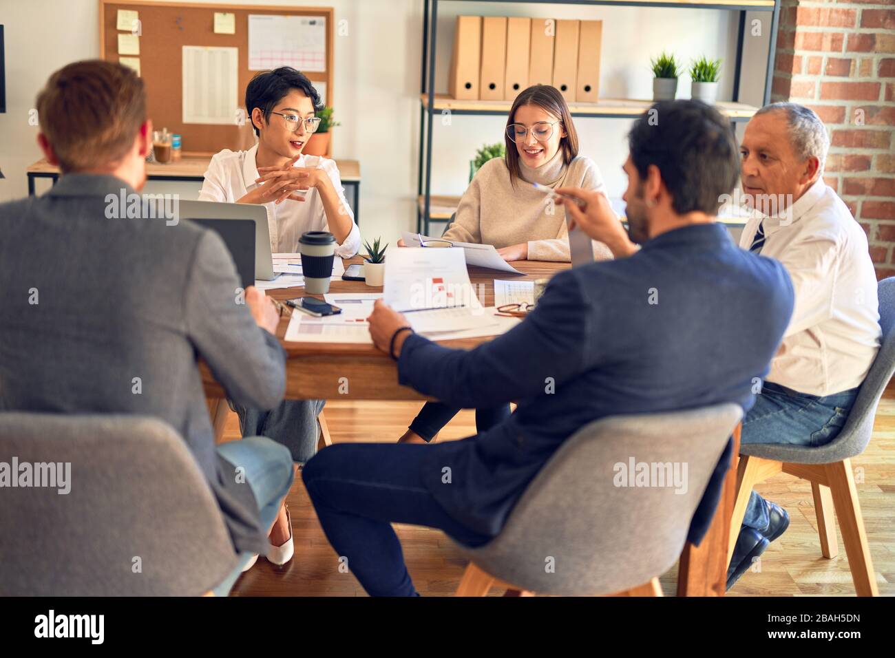Group of business workers working together. Sitting on desk using ...