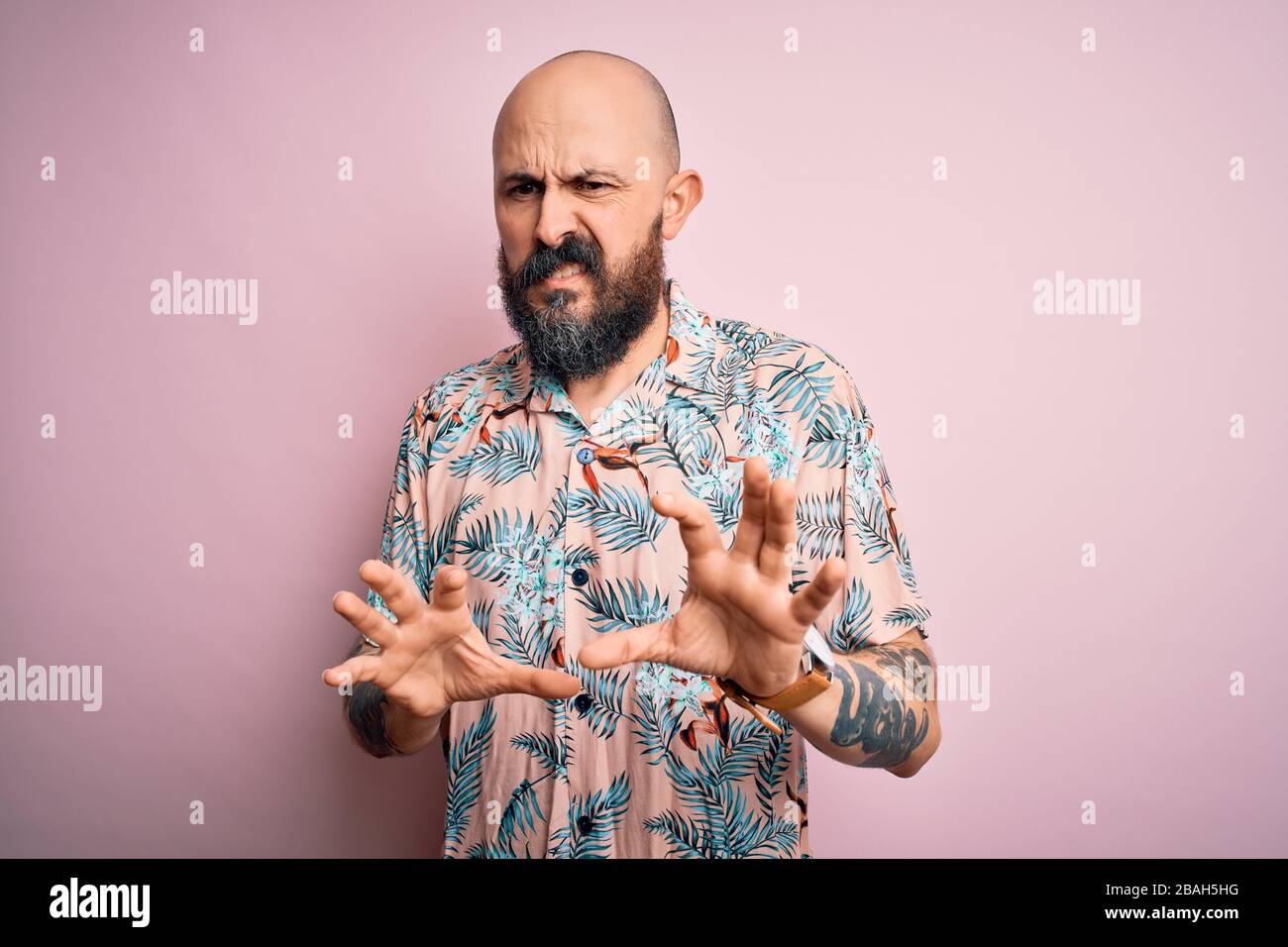 Handsome bald man with beard and tattoo wearing casual floral shirt ...