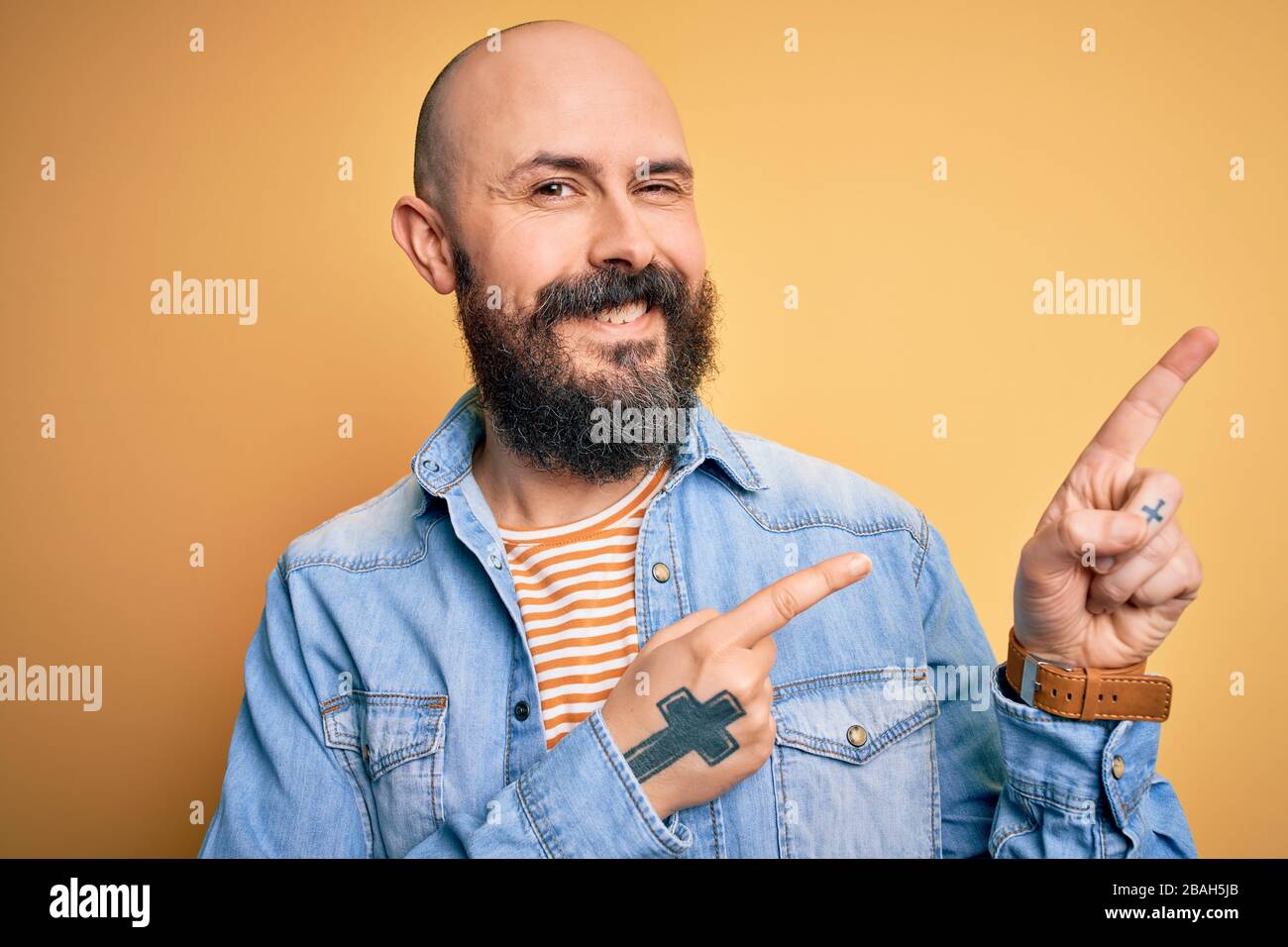 Handsome bald man with beard wearing casual denim jacket and striped t ...