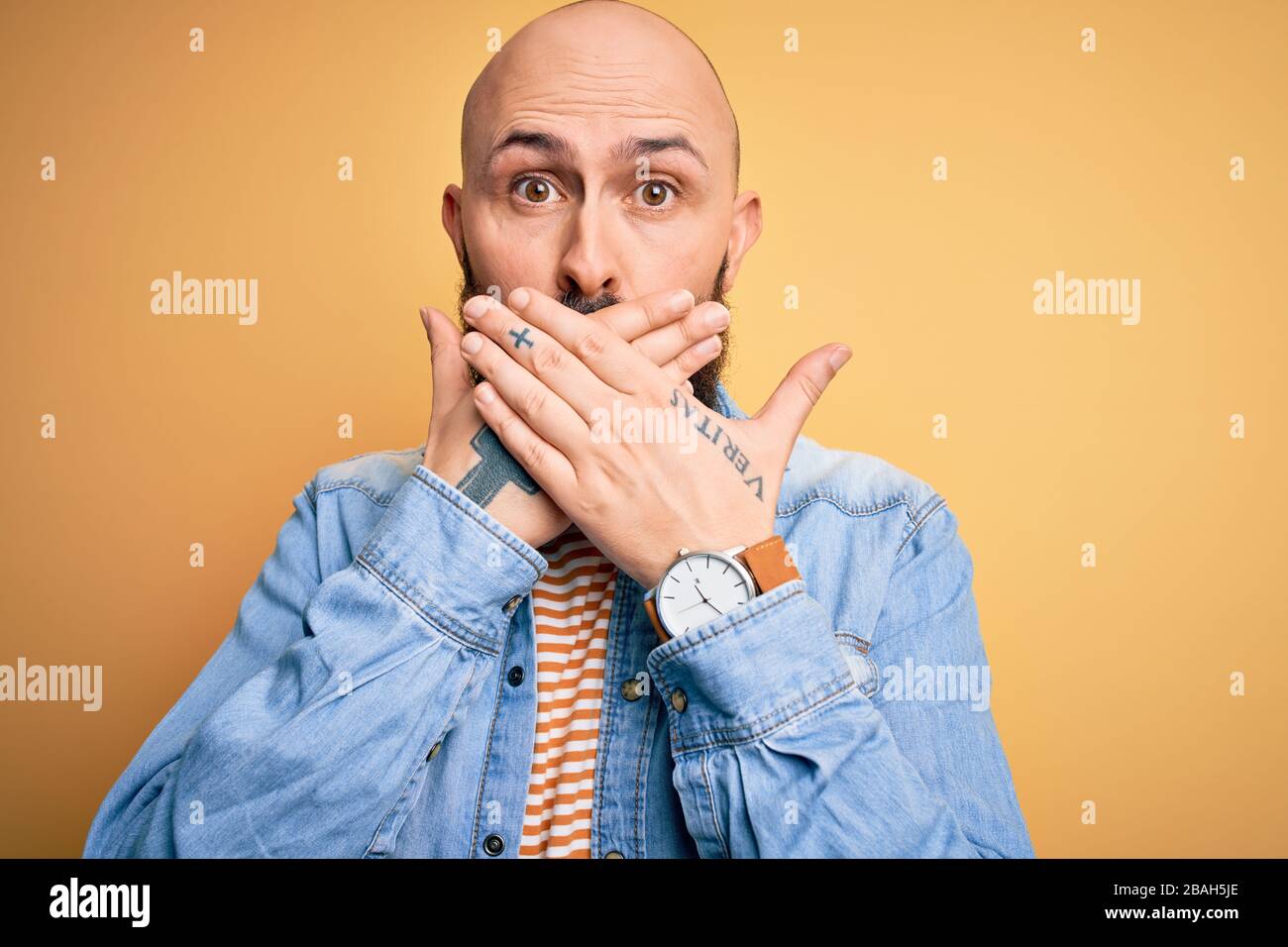 Handsome bald man with beard wearing casual denim jacket and striped t ...