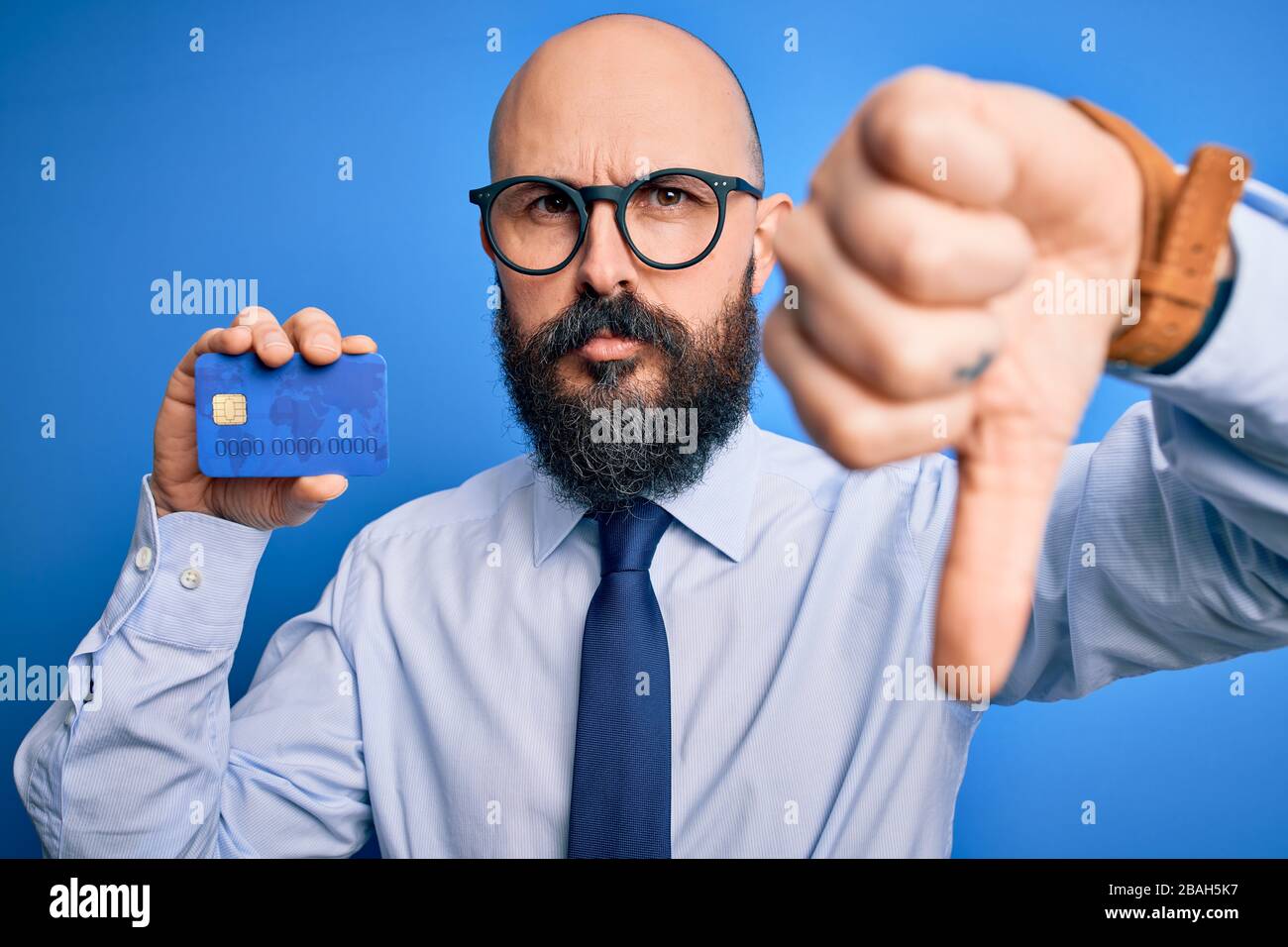 Handsome bald business man with beard holding credit card over isolated ...