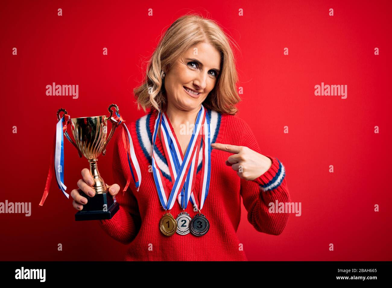 Middle age beautiful blonde successful woman wearing medals holding ...
