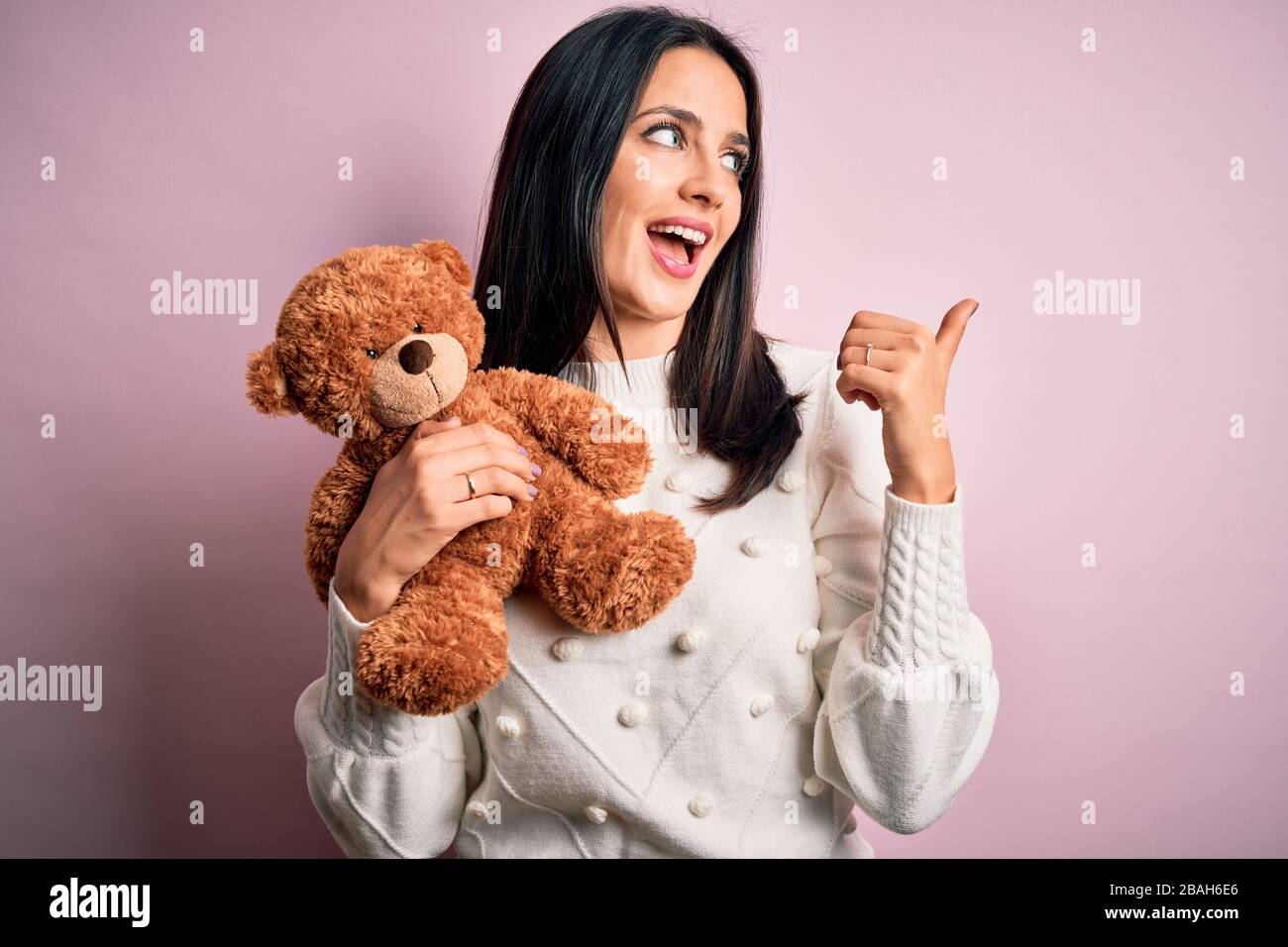 Young brunette woman with blue eyes hugging teddy bear stuffed animal ...