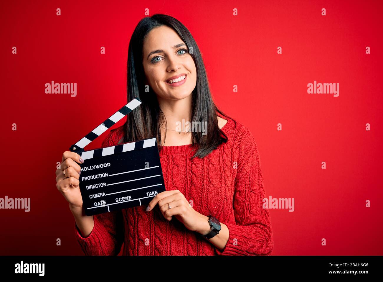 Young director woman with blue eyes making movie holding clapboard over ...