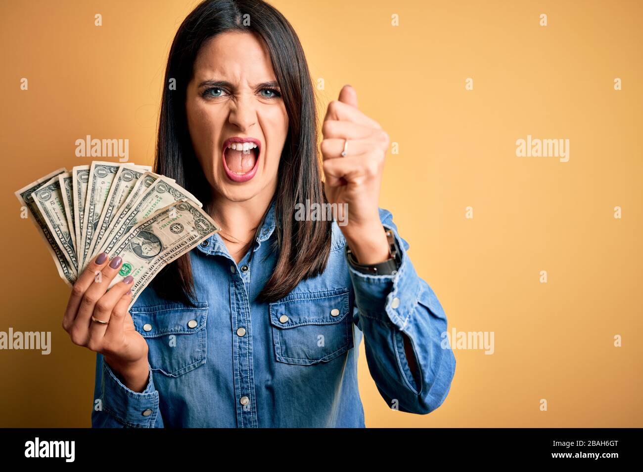 Young brunette woman with blue eyes holding 1 dollar banknotes over ...
