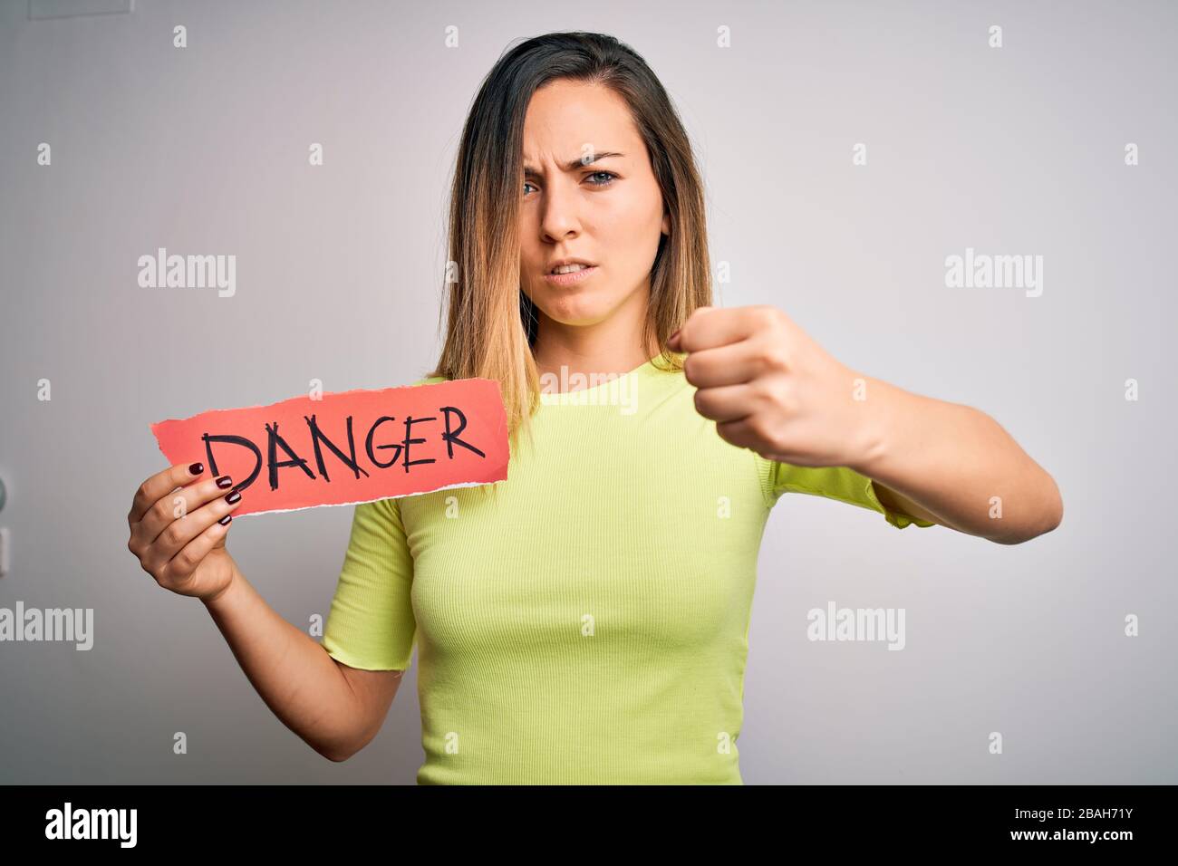Young beautiful blonde woman with blue eyes holding paper with danger ...