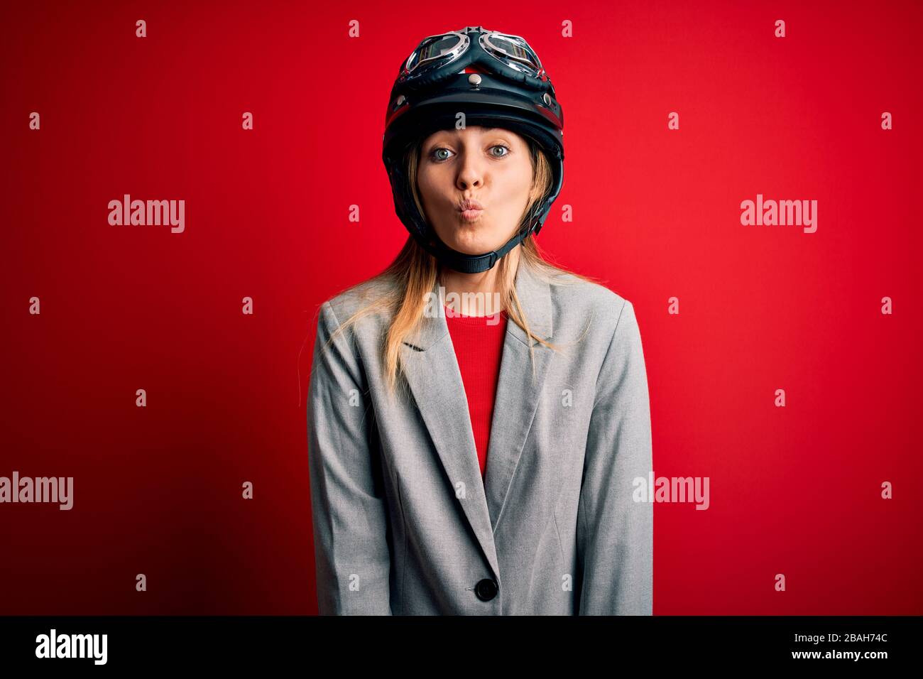 Young beautiful blonde motorcyclist woman wearing motorcycle helmet ...
