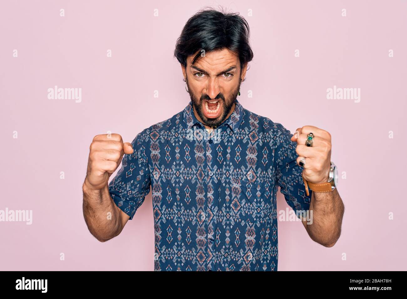 Young handsome hispanic bohemian man wearing hippie style over pink ...