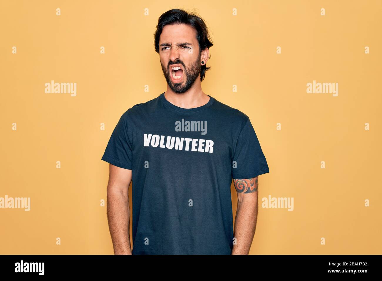Young handsome hispanic volunteer man wearing volunteering t-shirt as ...