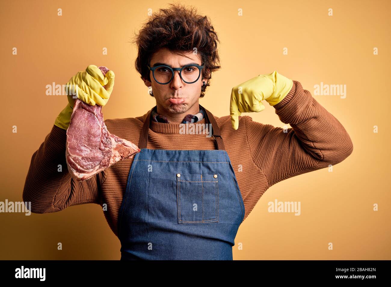 Young handsome butcher man holding meet steak standing over isolated ...