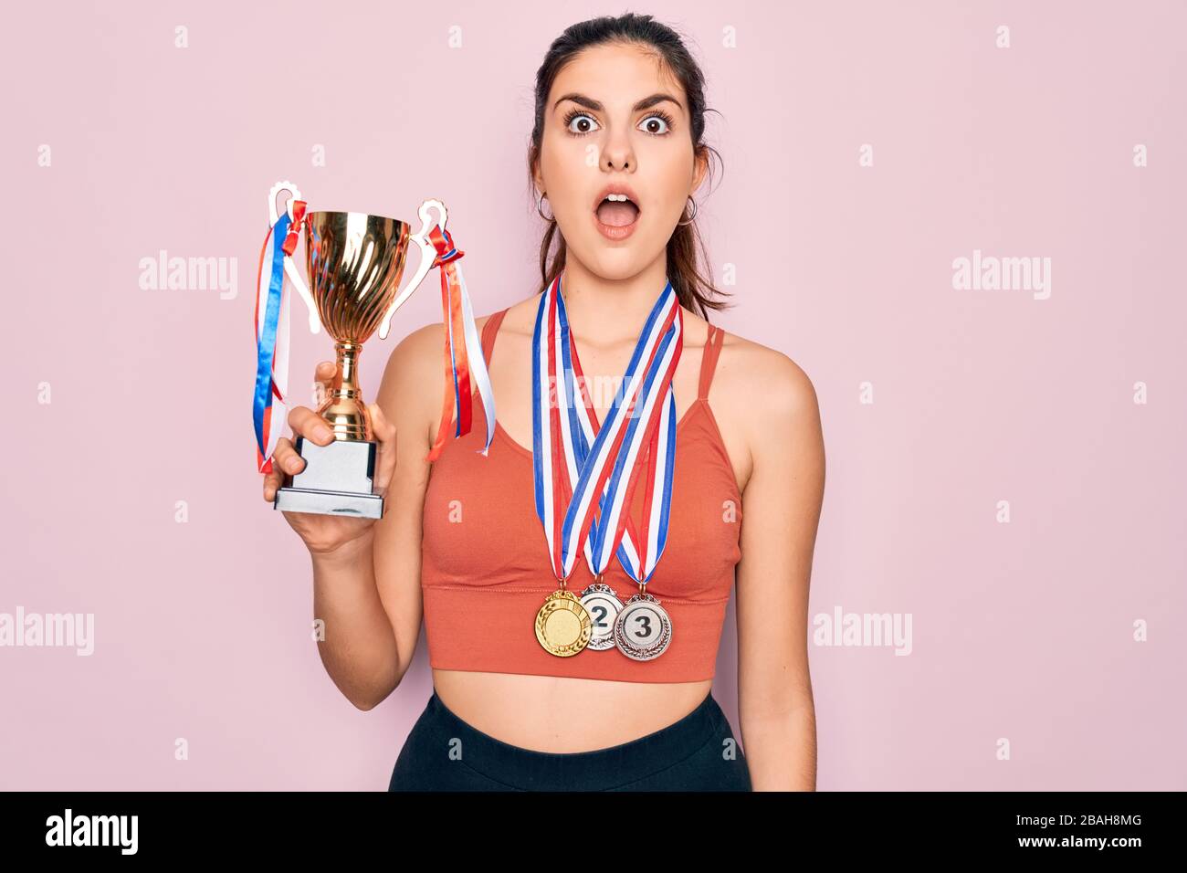 Young beautiful fitness winner athlete woman wearing sport medals and ...