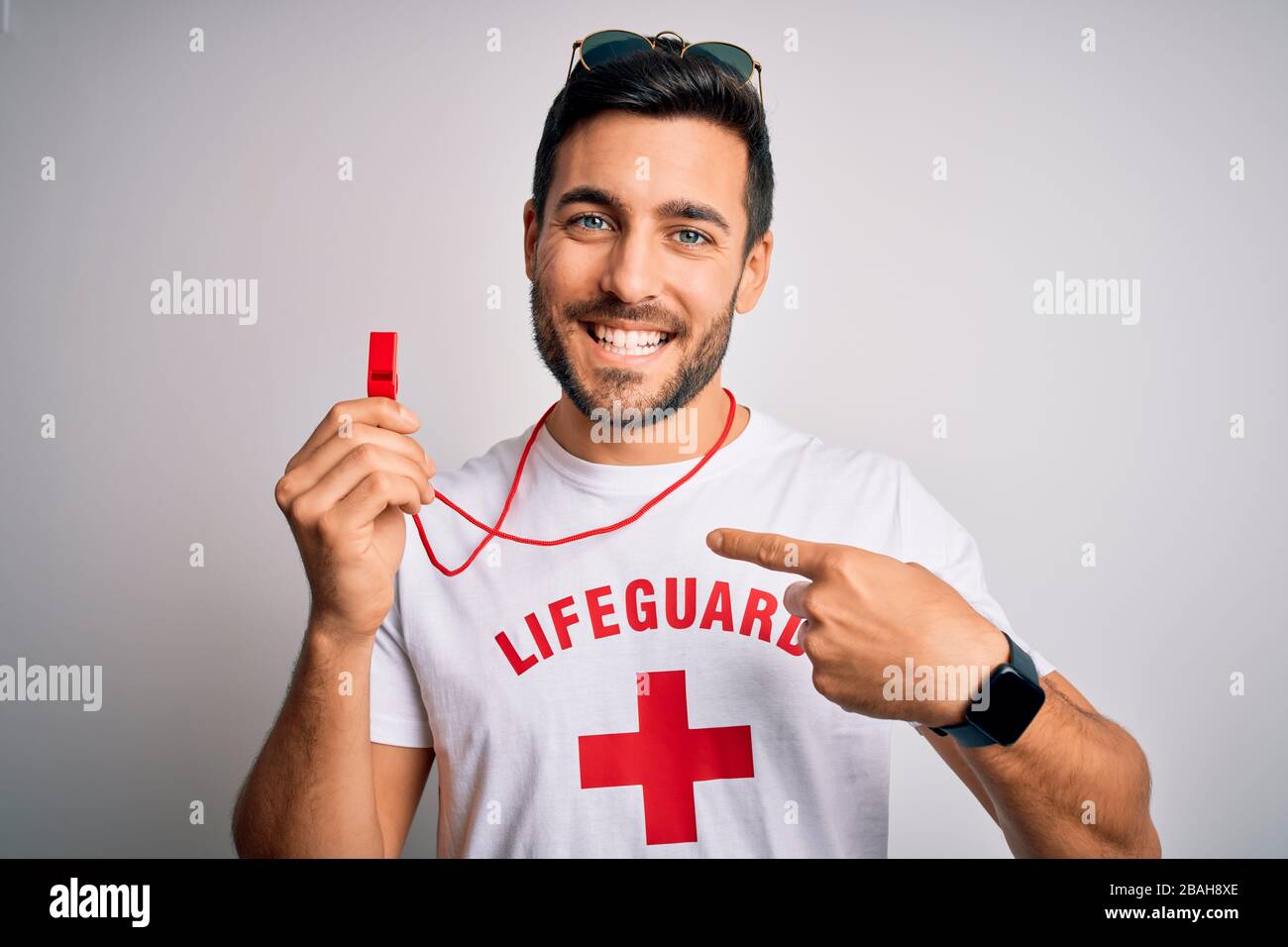 Young lifeguard man with beard wearing t-shirt with red cross and ...